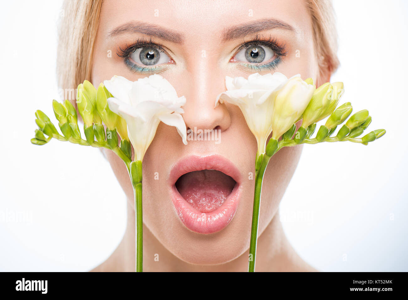 Attractive young woman with open mouth holding white flowers near face ...