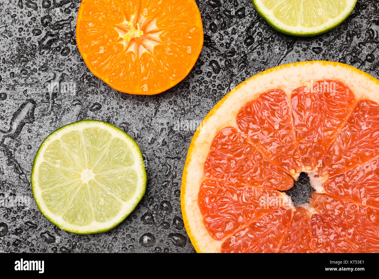 close up view of variety of fresh citrus fruits slices on wet table ...