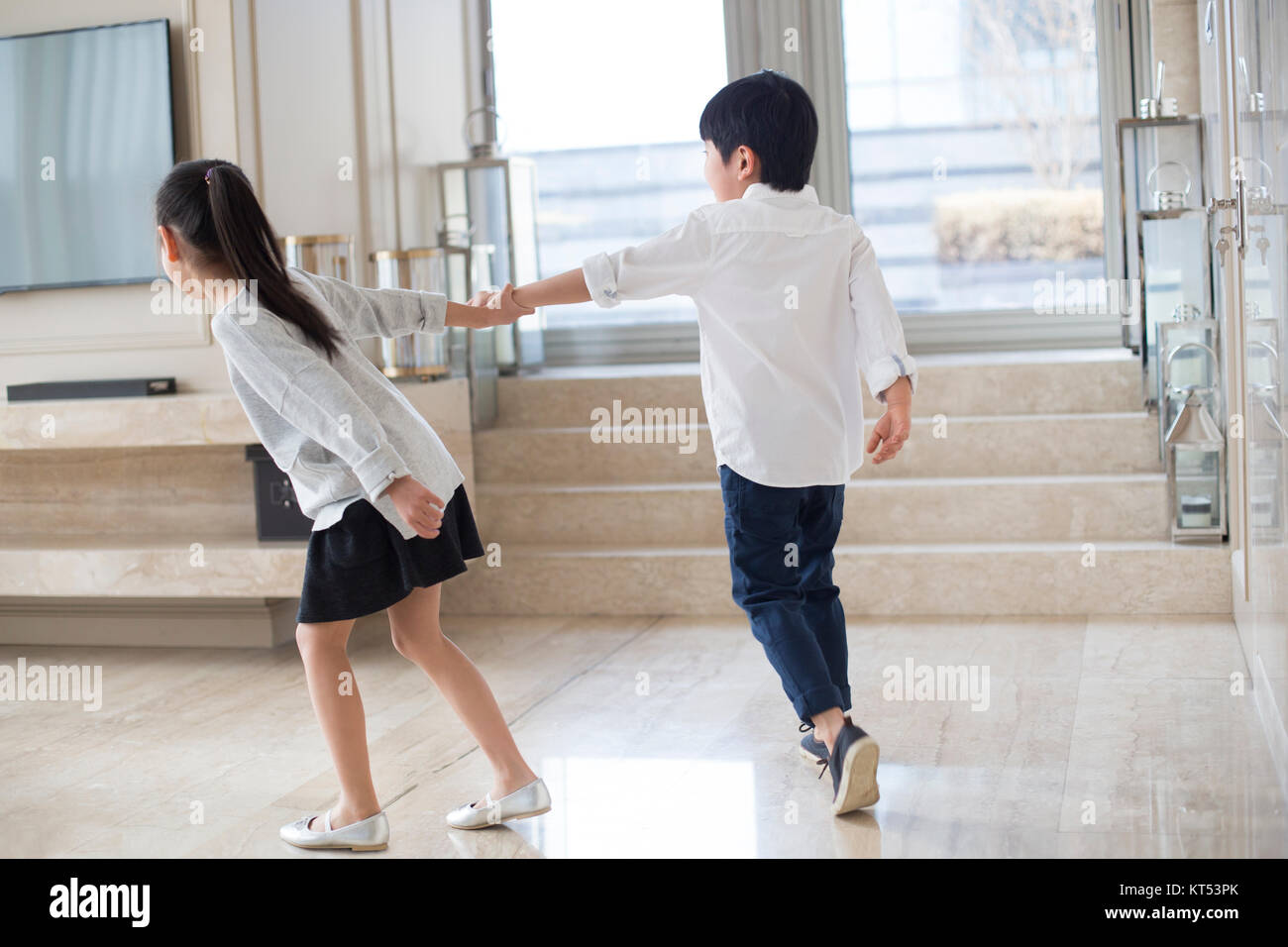 Happy siblings running in the living room Stock Photo - Alamy