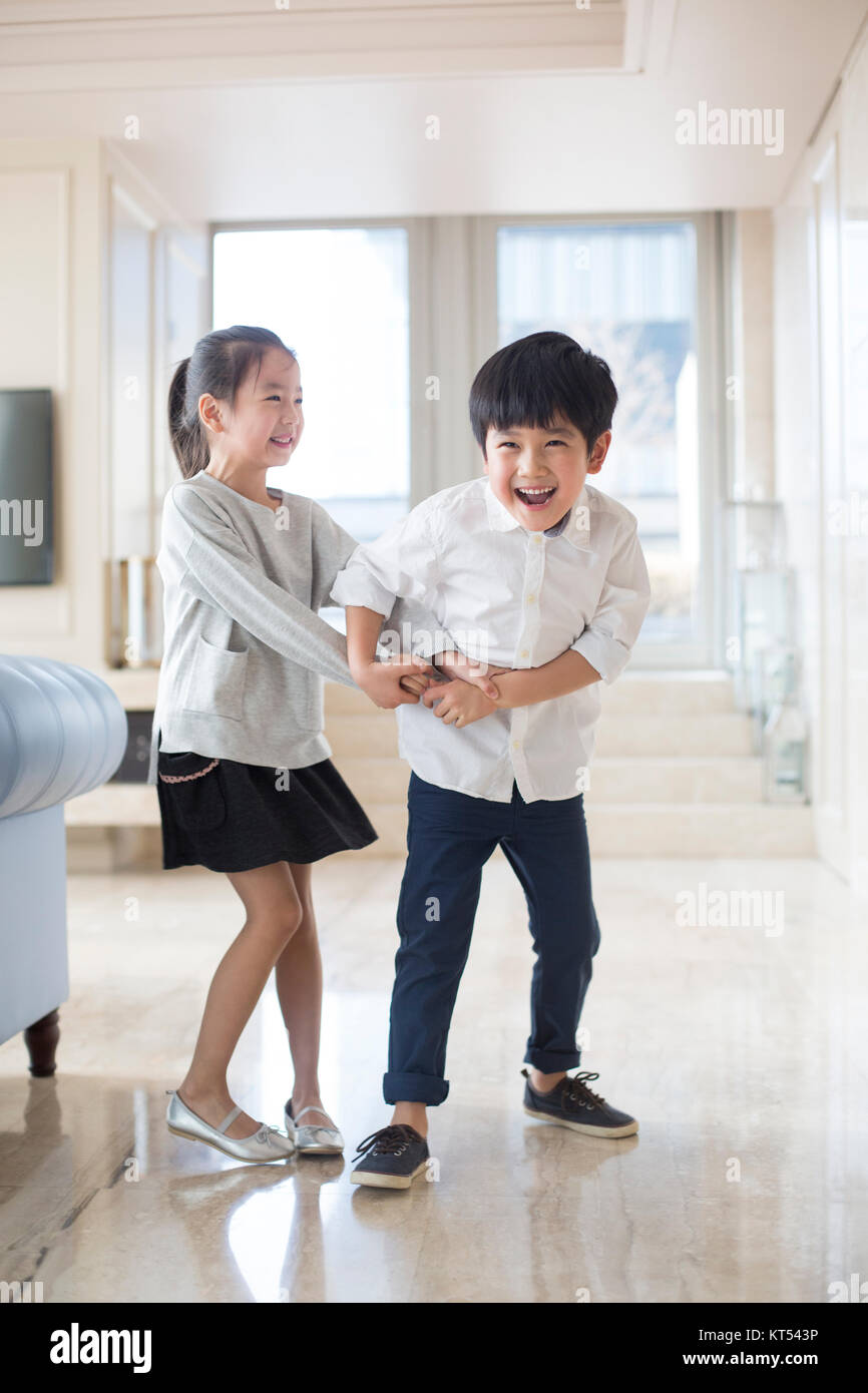 Happy siblings playing in the living room Stock Photo - Alamy