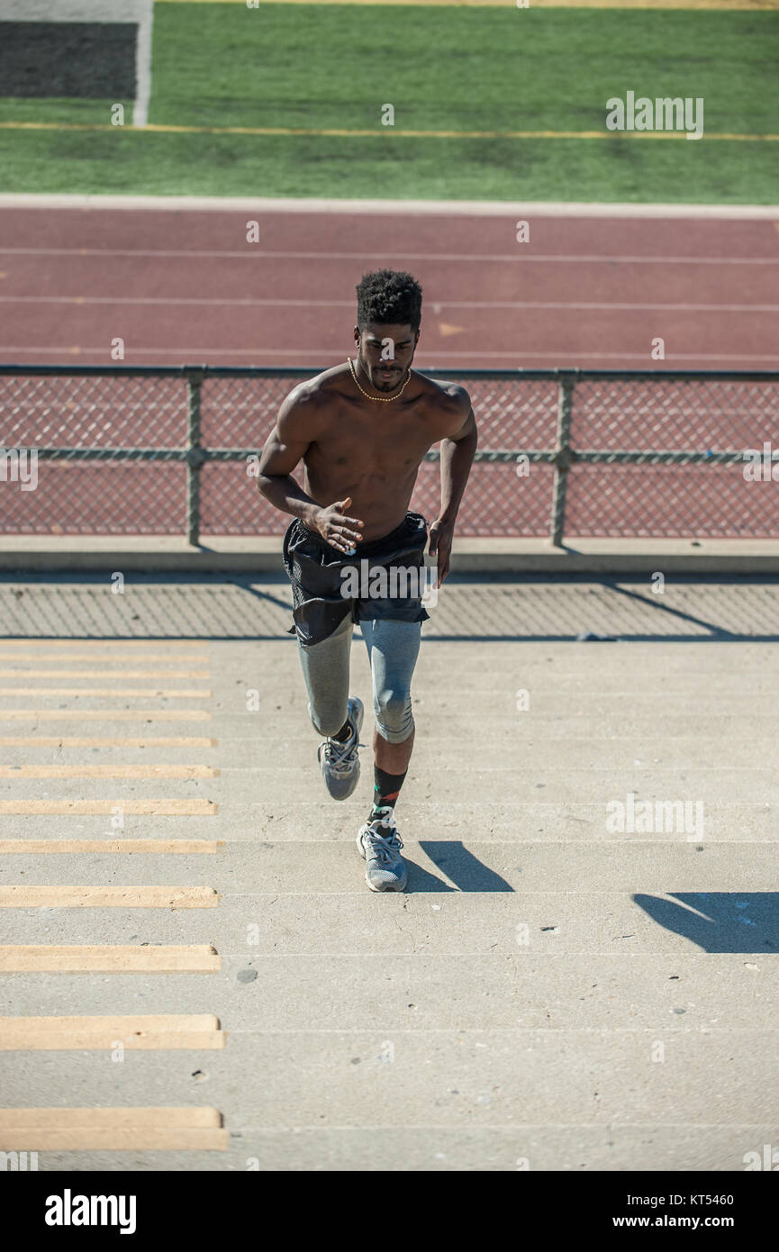 Front view of muscular Jamaican athlete powering up concrete steps at ...