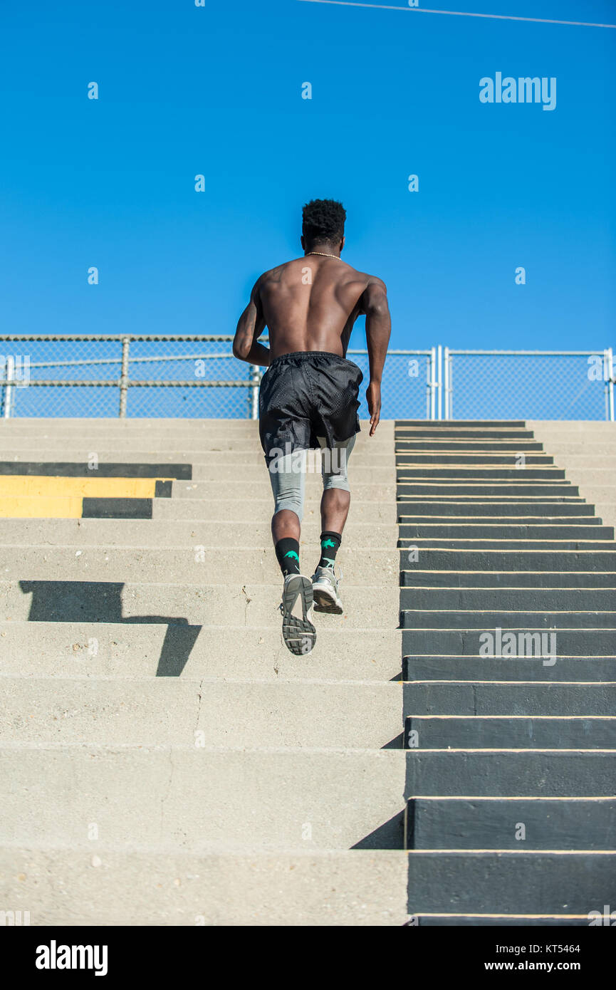 Muscular Jamaican athlete sprinting up plyometric workout at stadium ...