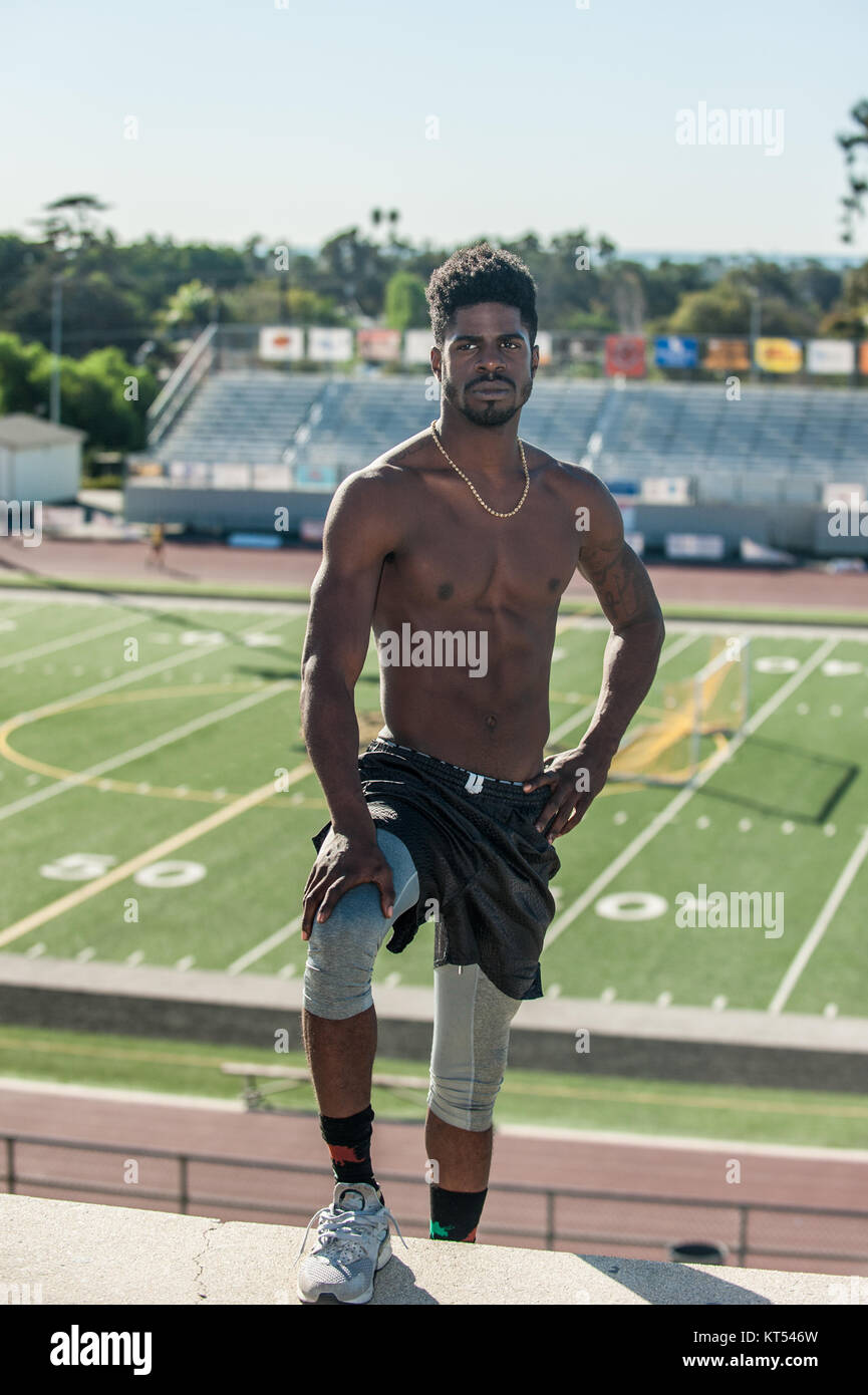 Muscular Jamaican athlete showing heroic strong pose at stop of stadium ...