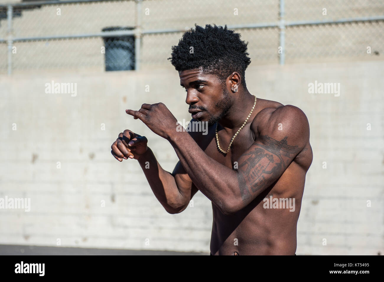 Muscular Jamaican boxer with guard up while shadowboxing on stadium ...