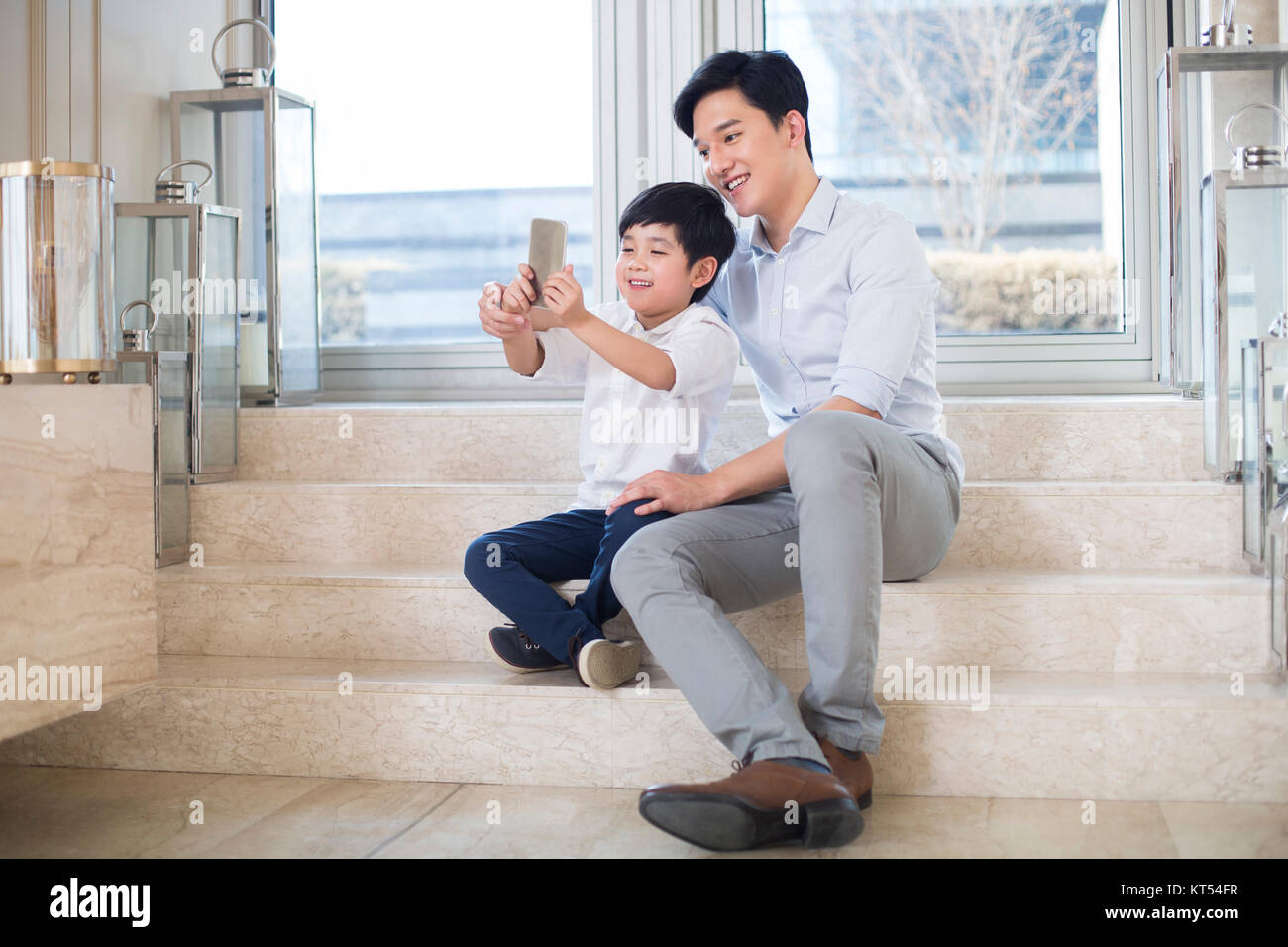 Cheerful father and son taking self portrait in the living room Stock ...