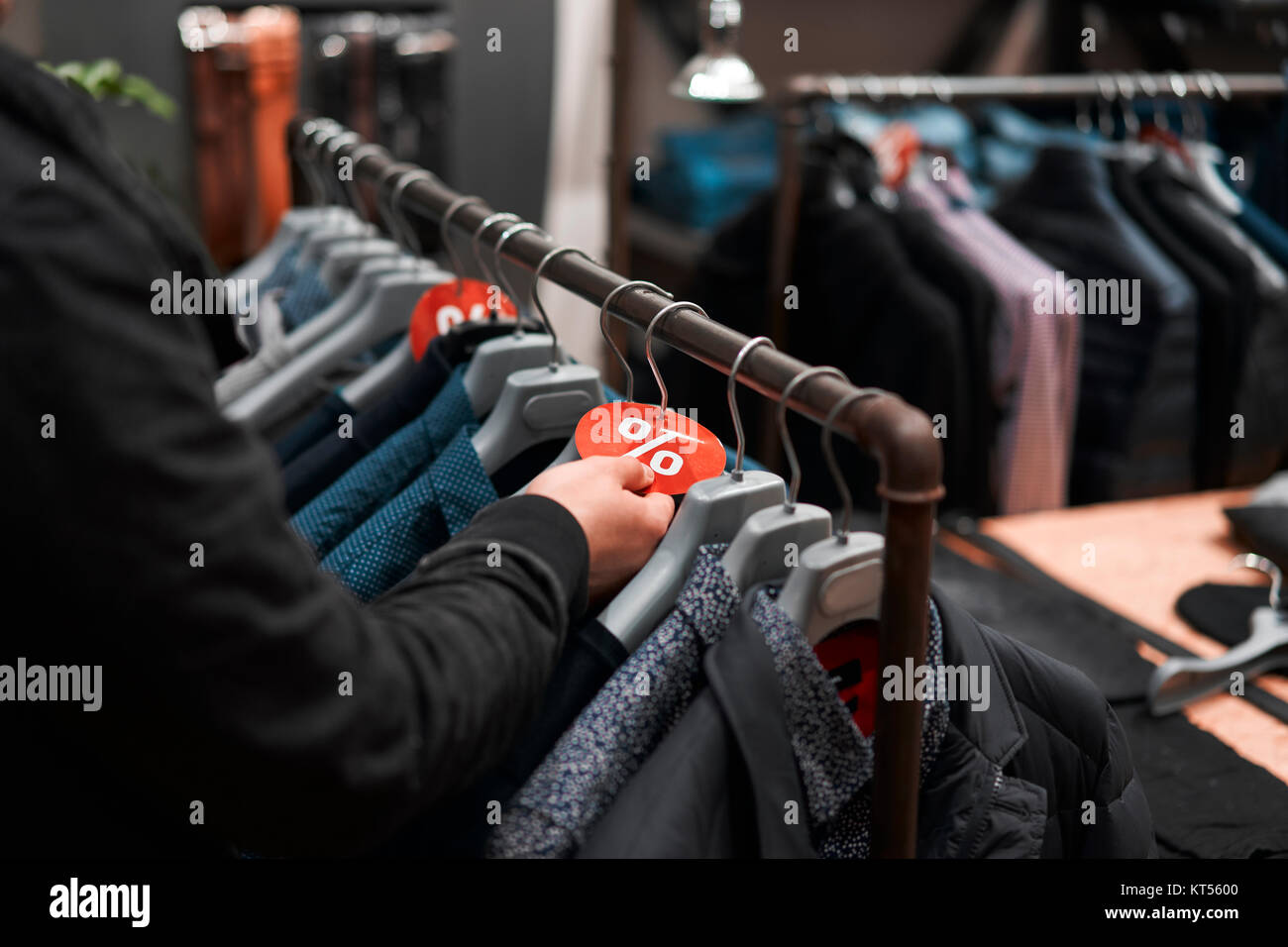 man chooses the clothes hanging on hangers in shop Stock Photo - Alamy