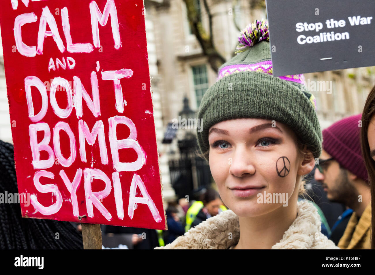 A protester with a peace symbol on her cheek holds a placard 'Keep Calm ...