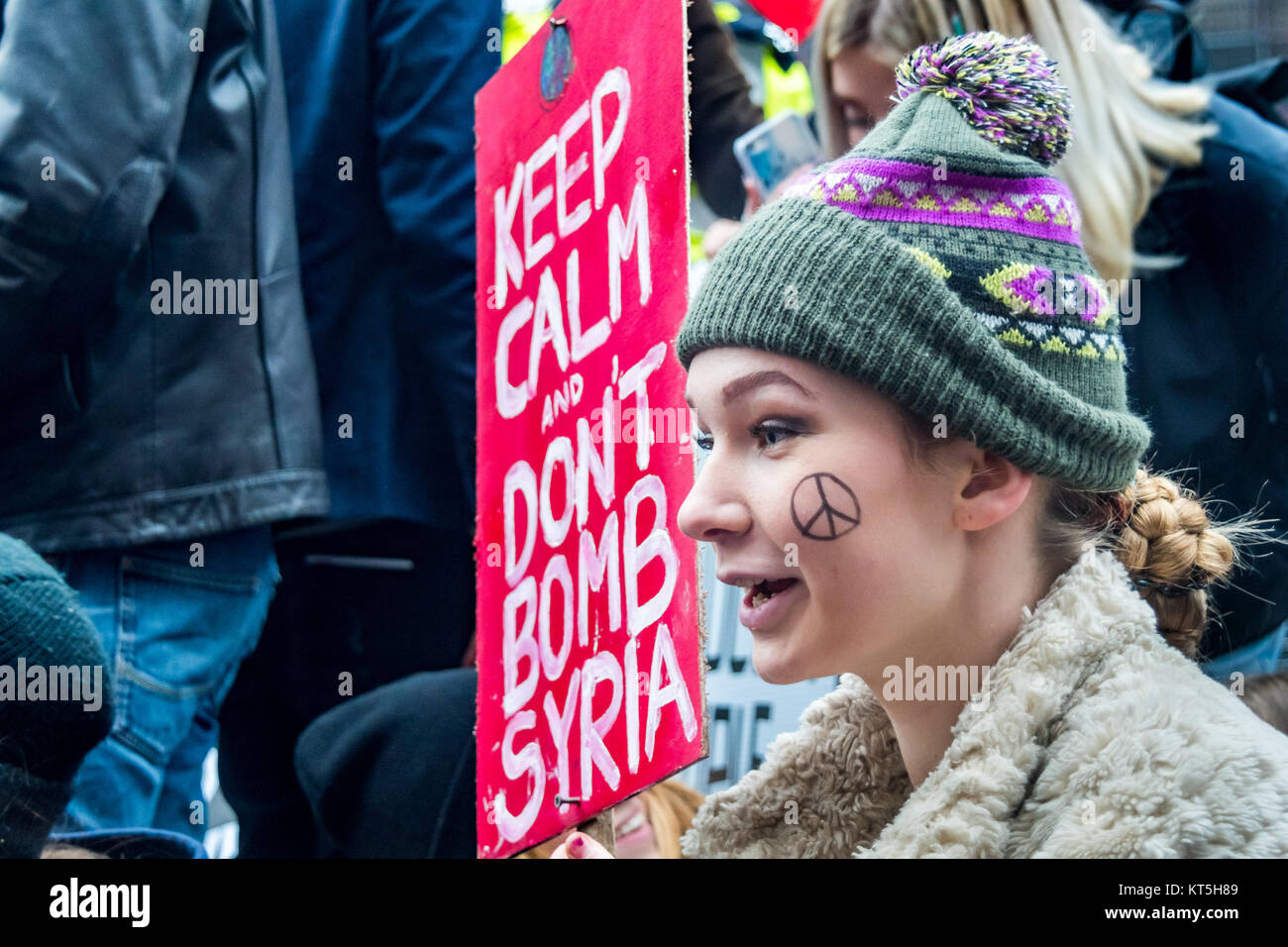 A protester with a peace symbol on her cheek holds a placard 'Keep Calm ...