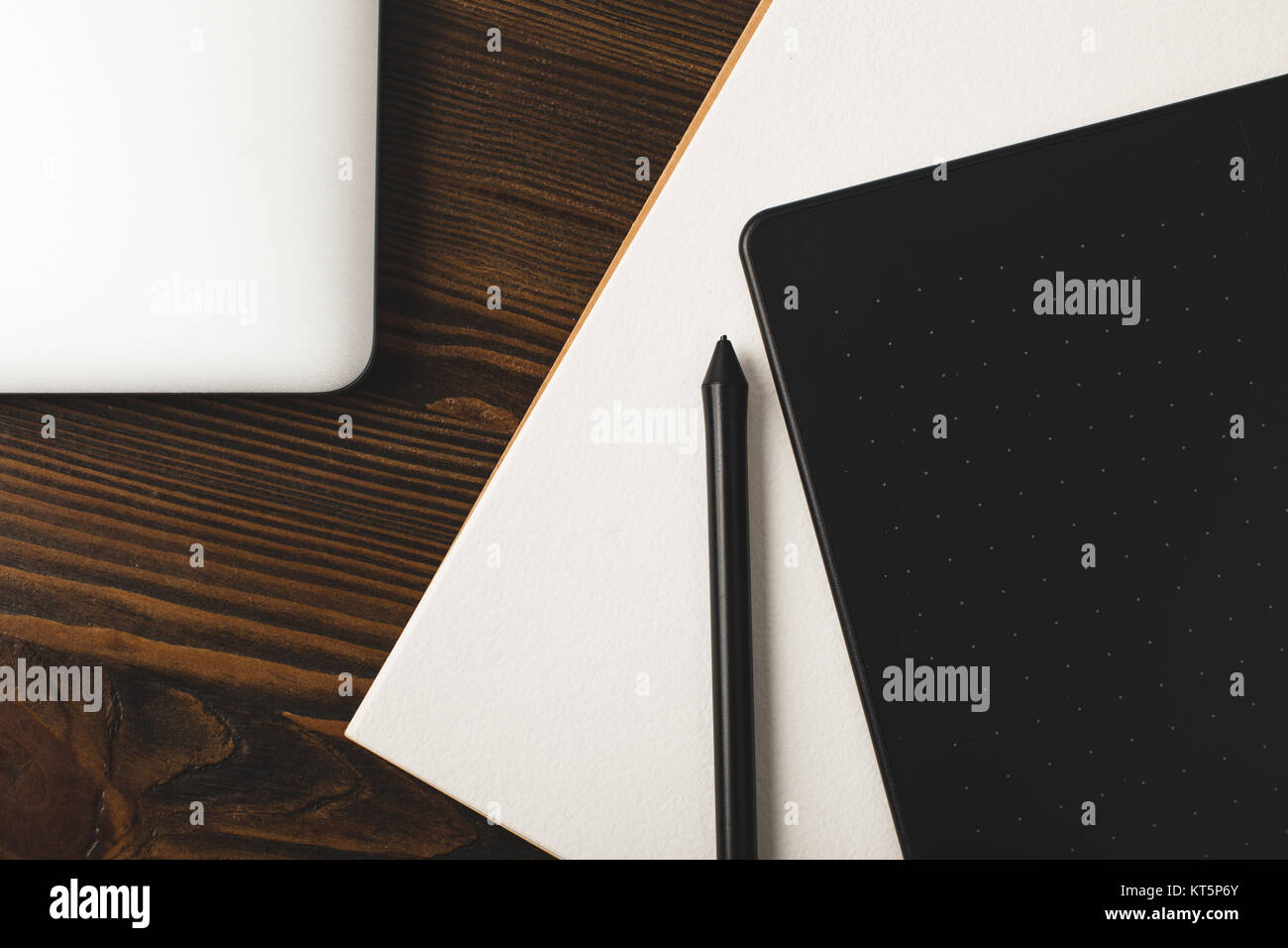 top view of graphics tablet, laptop and drawing album on wooden table ...