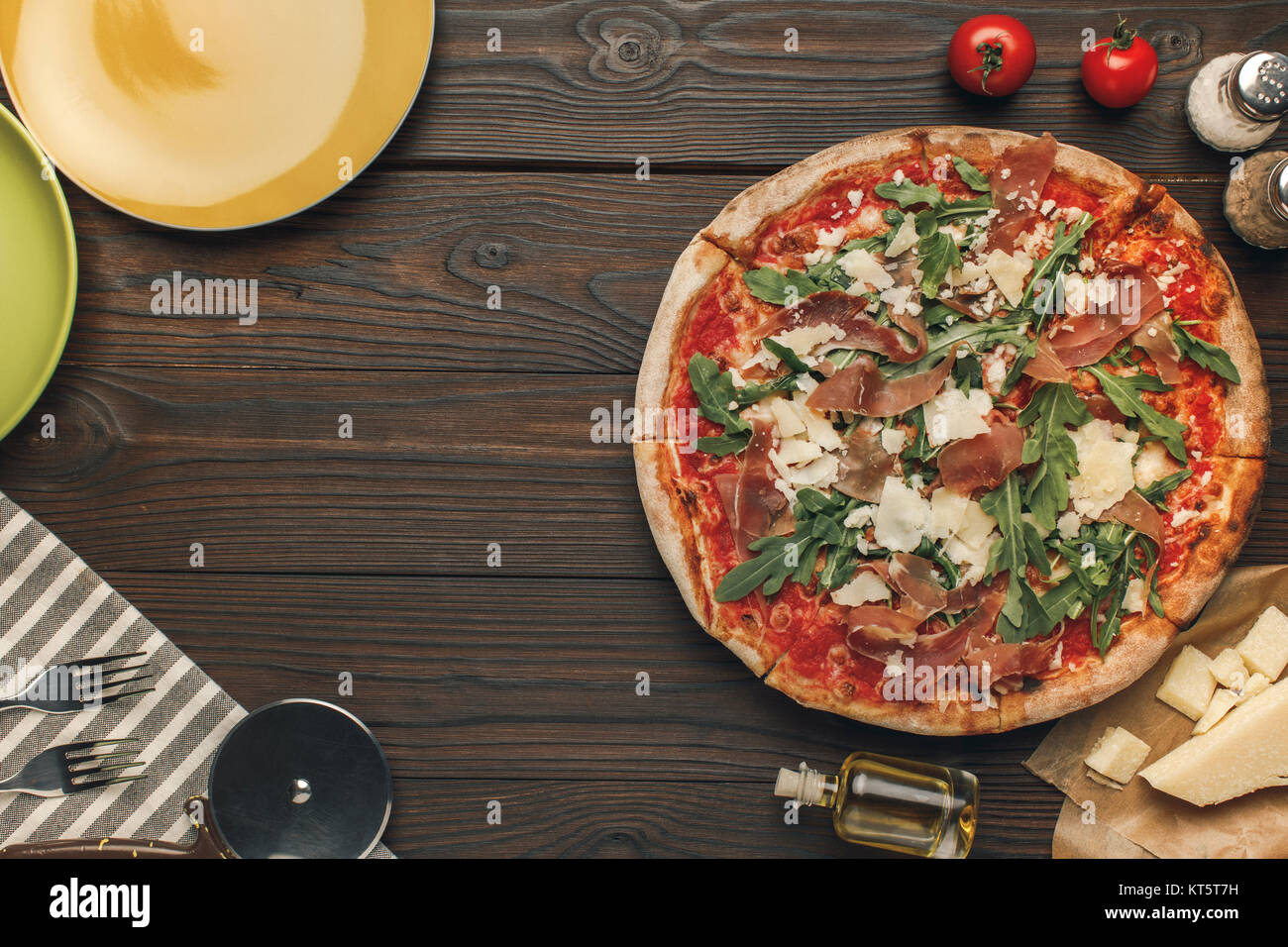 flat lay with arranged italian pizza, cutlery and various ingredients ...