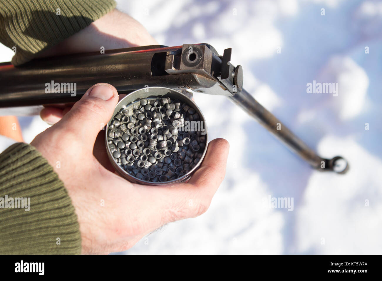 a man in a camouflage jacket holding a bb gun and a box of buckshot ...