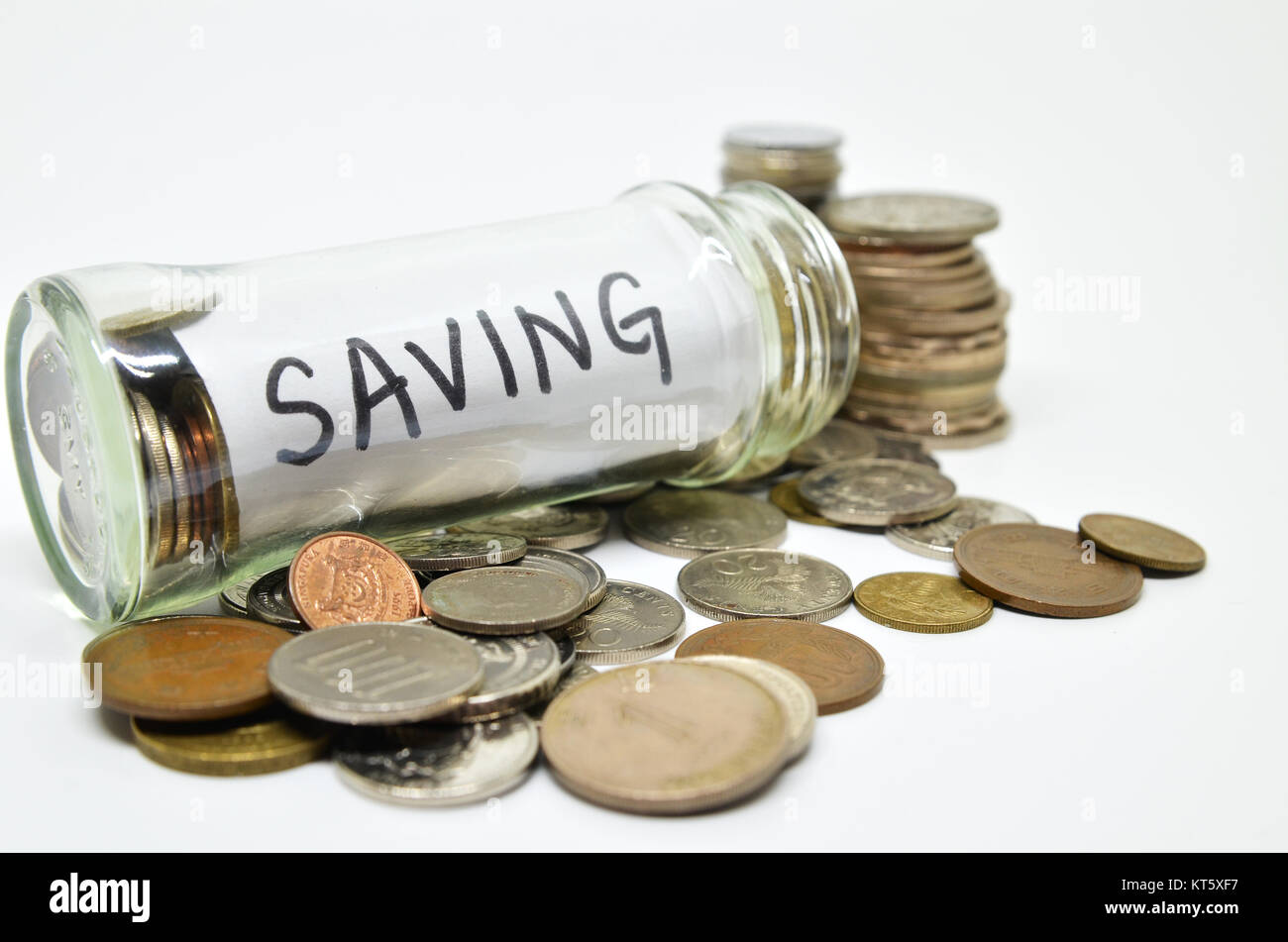 Saving lable in a glass jar with coins spilling out Stock Photo - Alamy