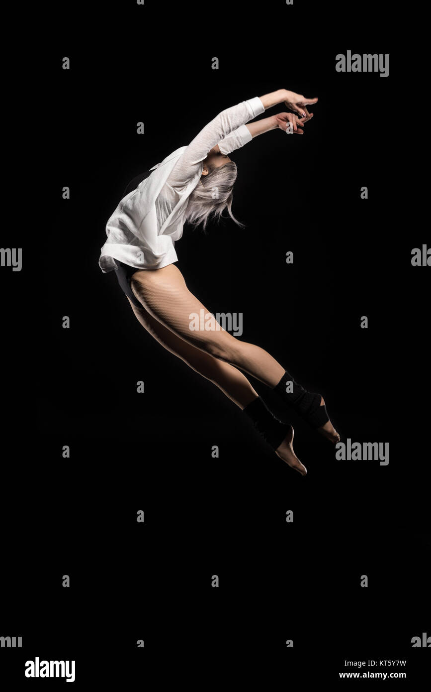 side view of jumping woman in bodysuit on black Stock Photo - Alamy