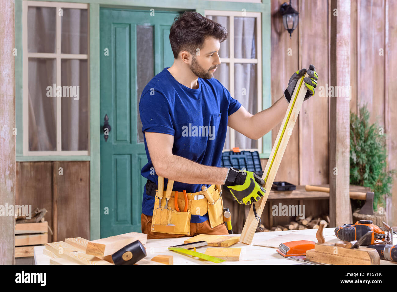 side view of concentrated carpenter taking measures of wooden plank on ...