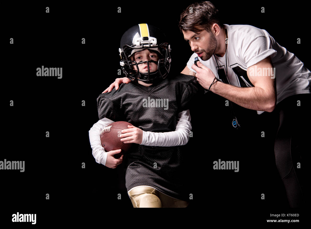 Coach looking at boy american football player running with ball Stock ...