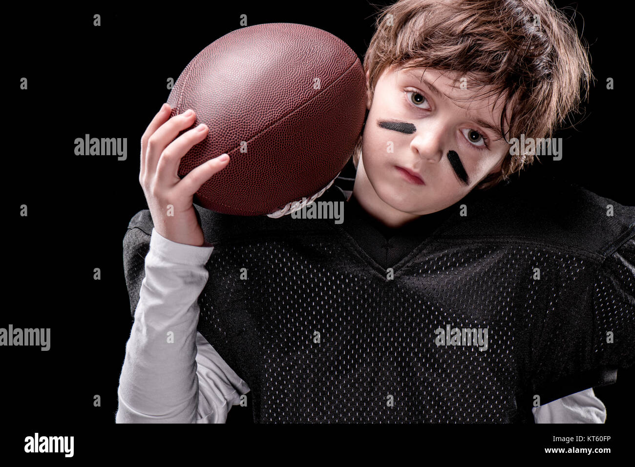 Upset boy american football player holding rugby ball and looking at ...