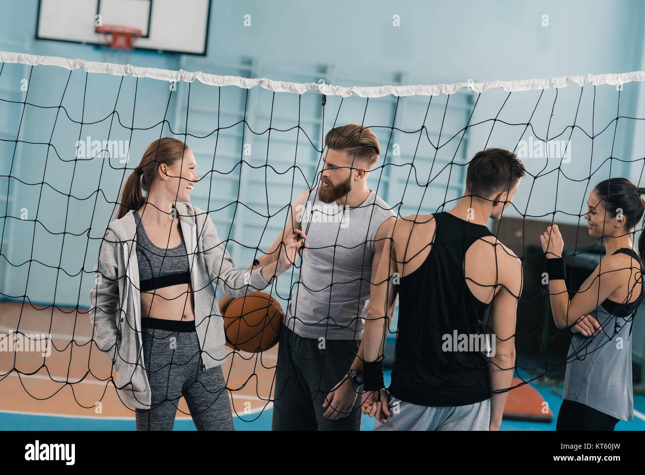 Sporty young people with ball standing near net in sports hall Stock ...