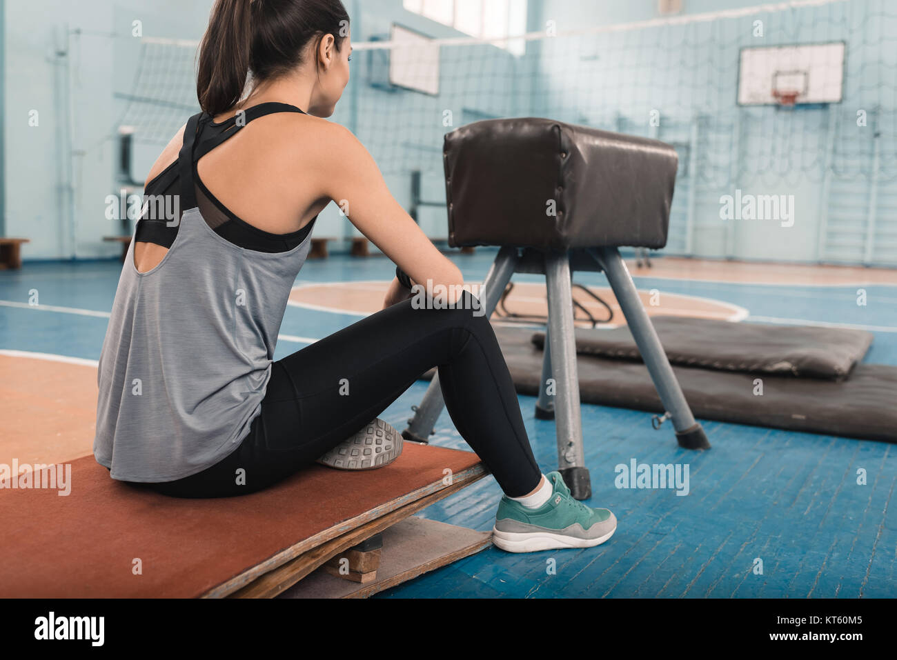 Back view of young sportswoman sitting and looking at distance in ...
