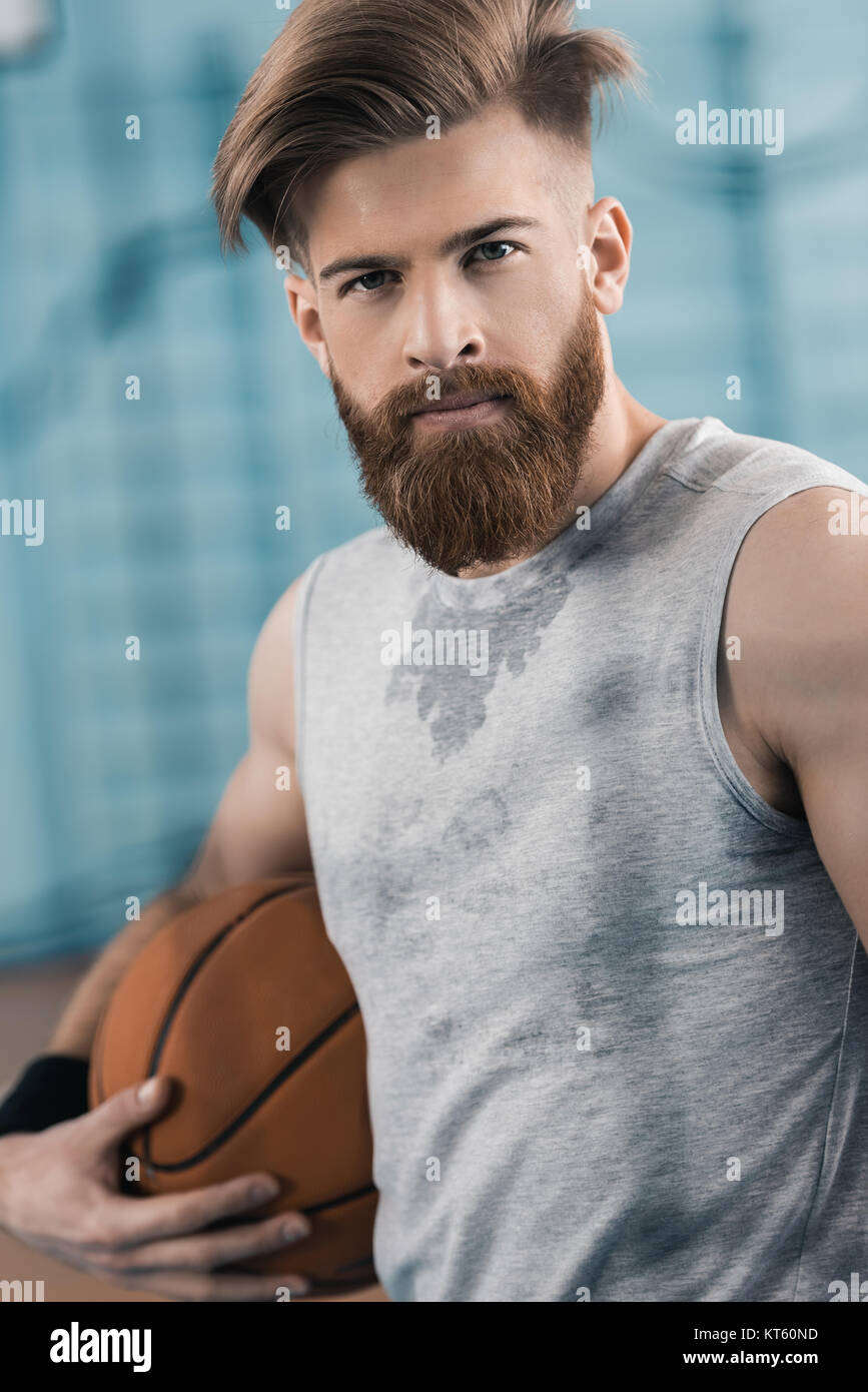 Bearded young basketball player holding ball and looking at camera ...