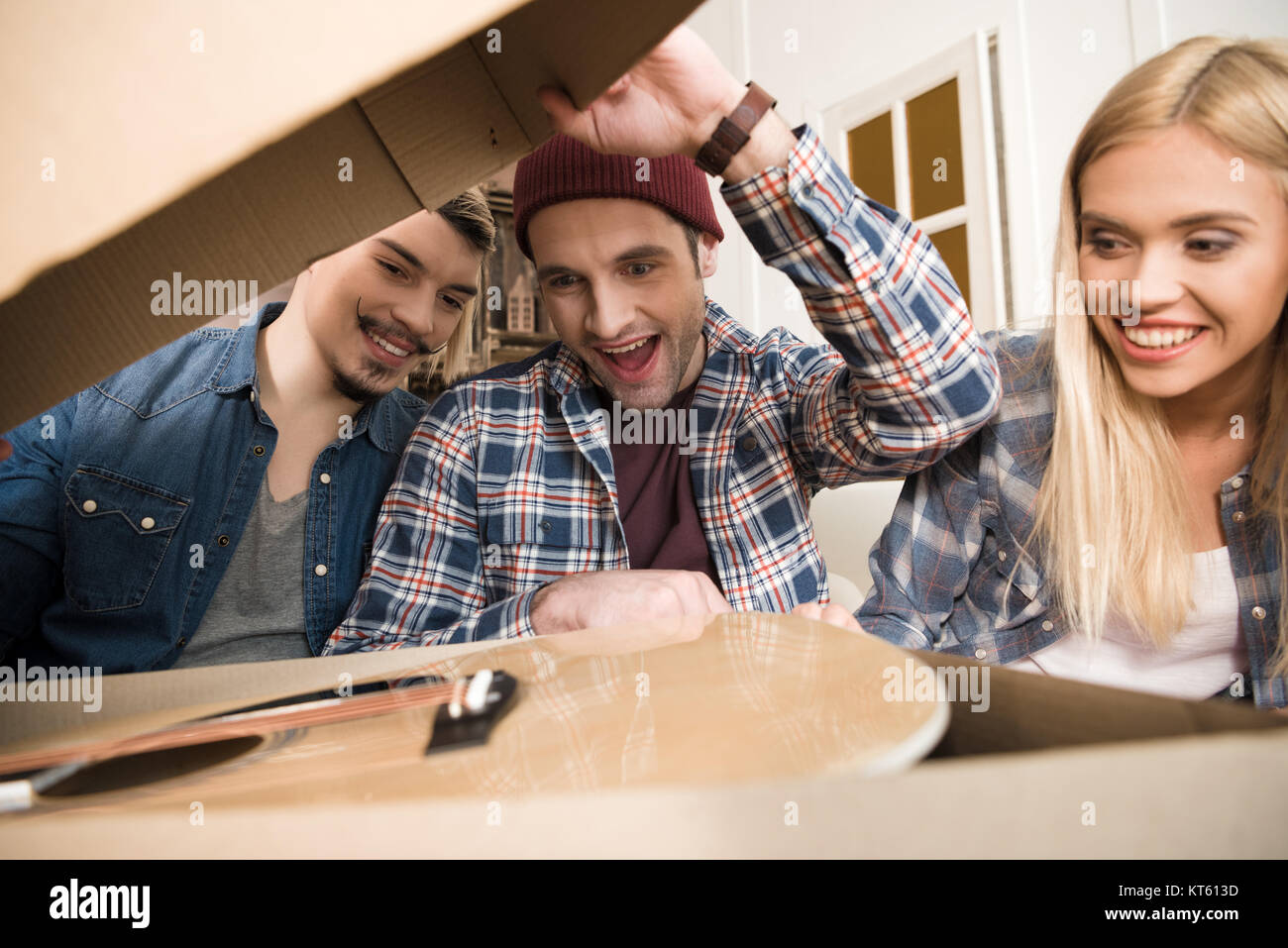 Close-up view of excited young friends opening box with guitar Stock ...