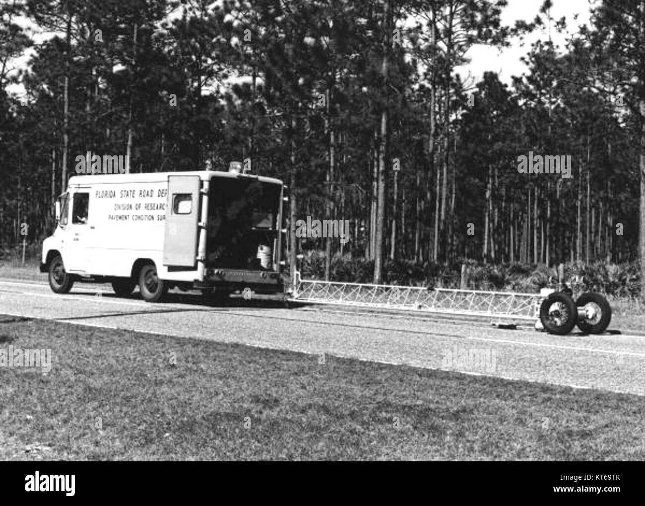 A van is seen pulling a road profilometer, an instrument used to ...