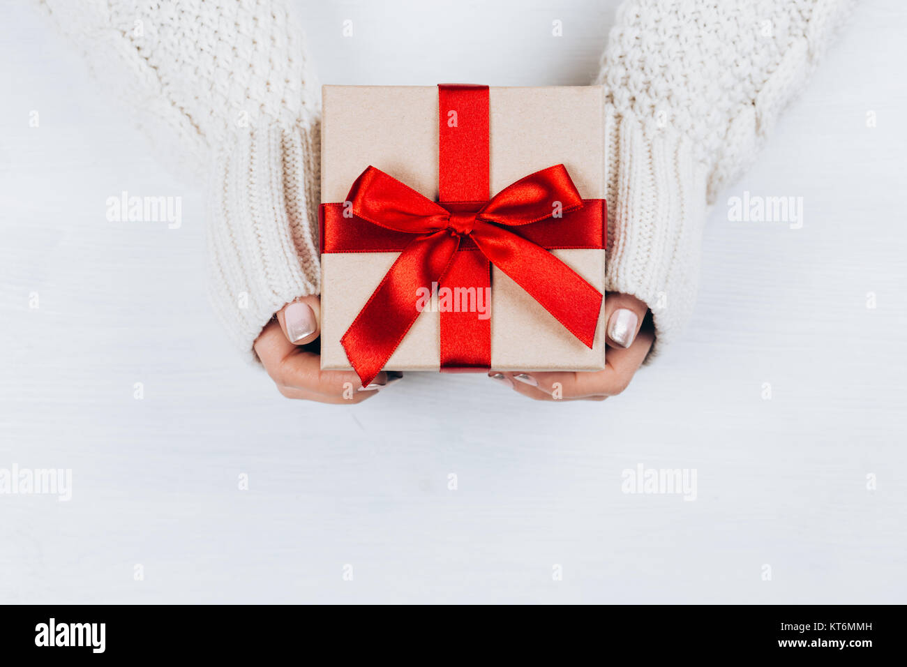 Female hands holding present with red bow Stock Photo - Alamy