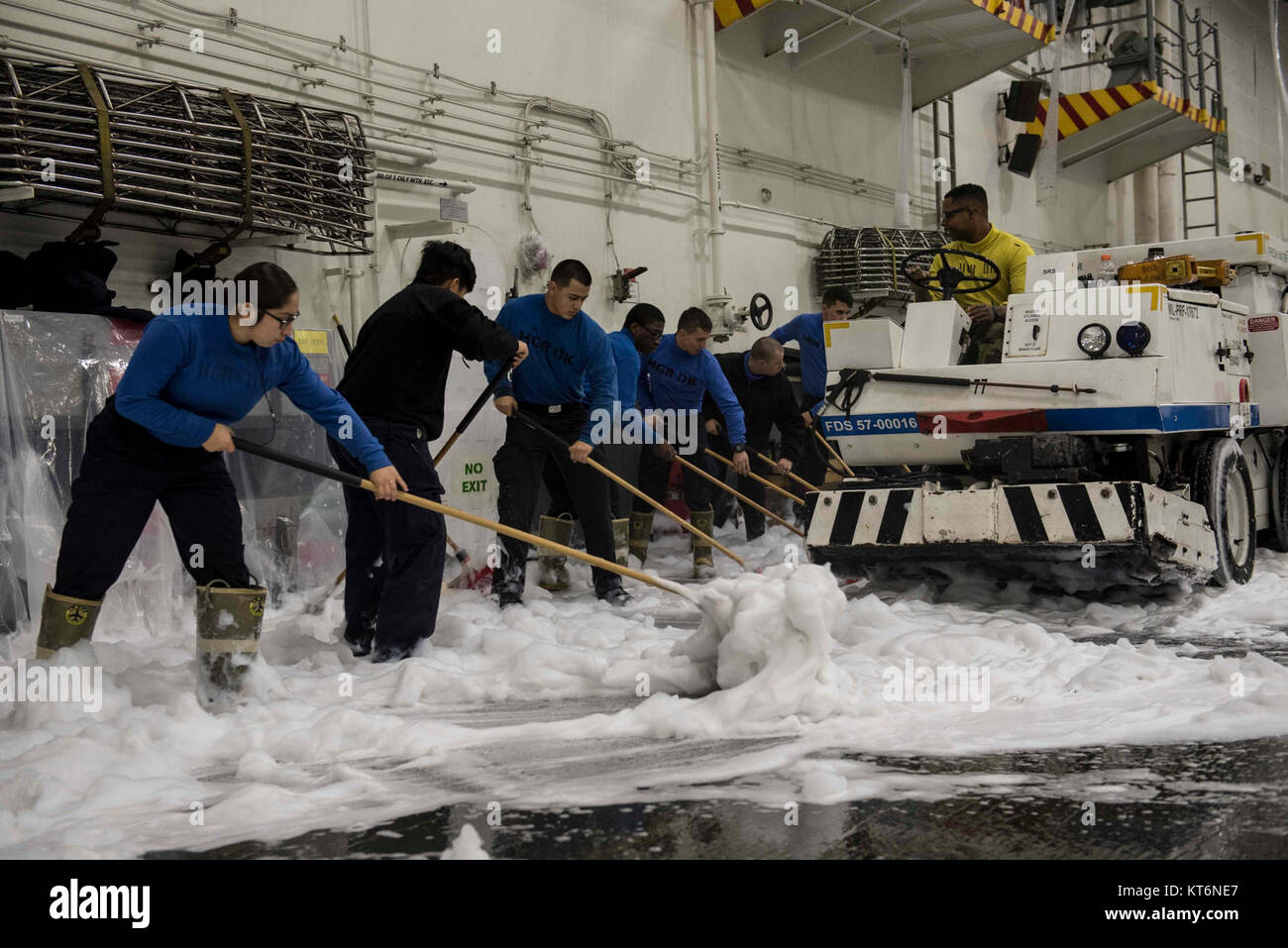 Sailors clean the hangar bay after testing the aqueous film forming ...