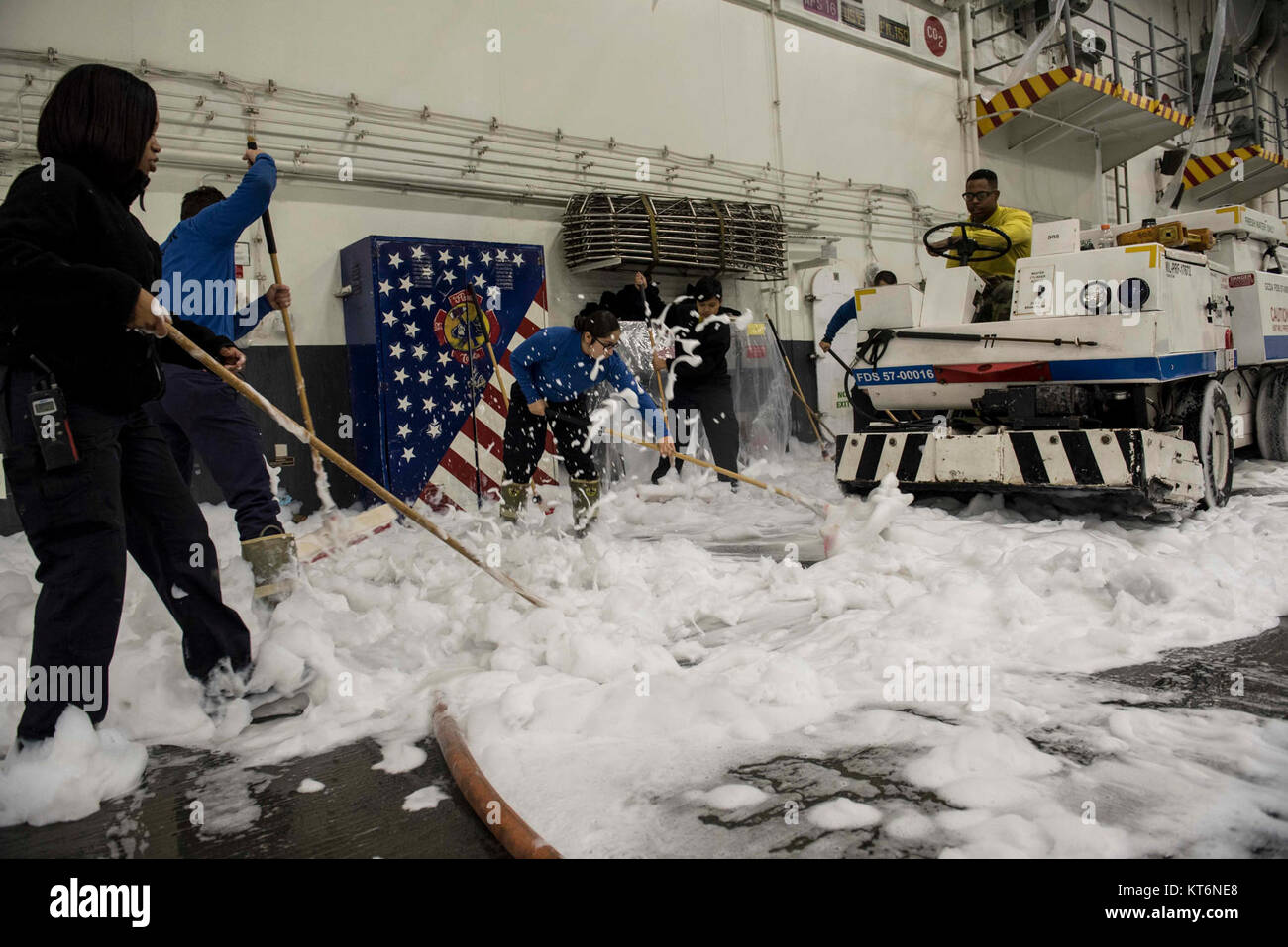 Sailors clean the hangar bay after testing the aqueous film forming ...