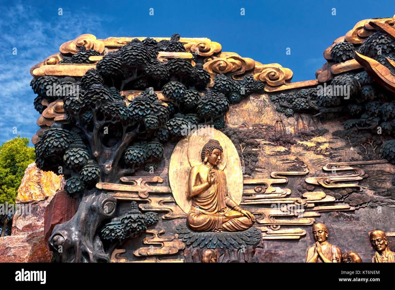 A large metal mural depicting many different Buddhist scenes at the ...