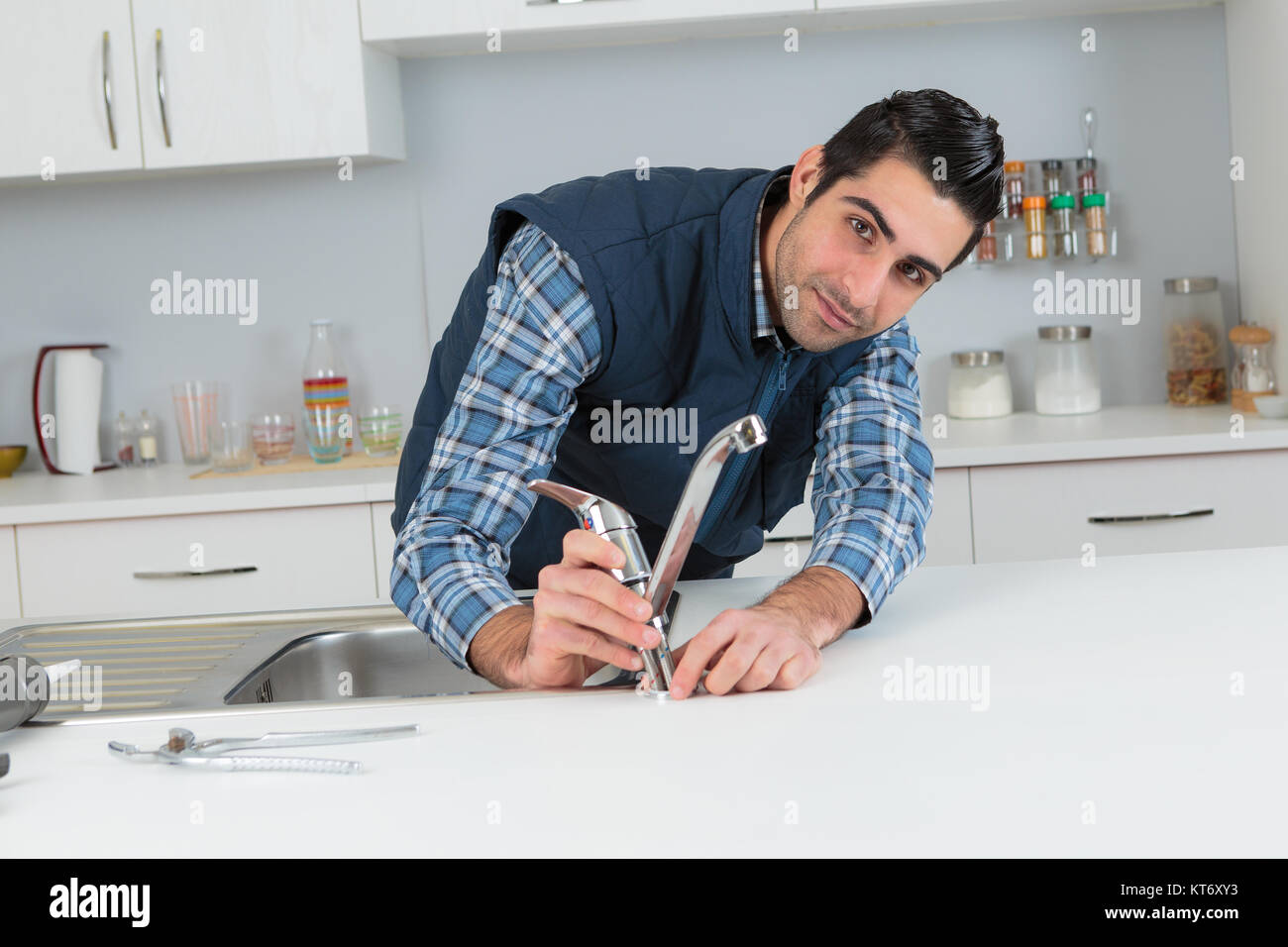 happy man fixing tap with tool in the kitchen Stock Photo - Alamy