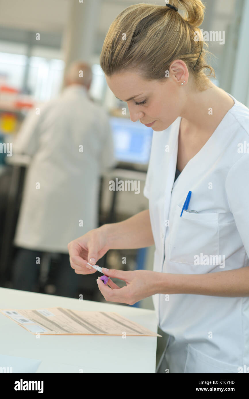 Nurse putting identification sticker on vial of blood Stock Photo - Alamy