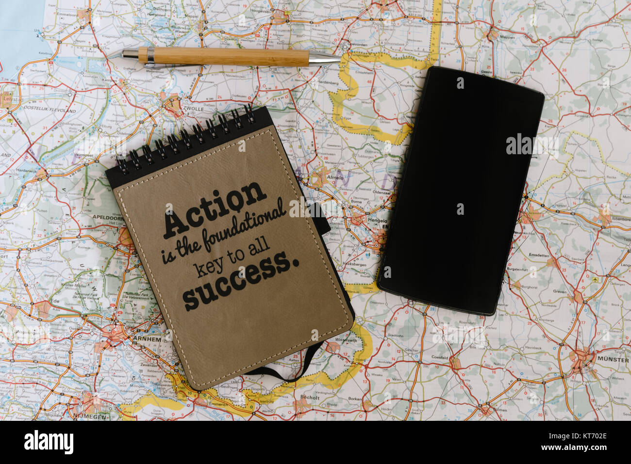 Lay flat of map, notebook with motivational quote, phone and pen ...