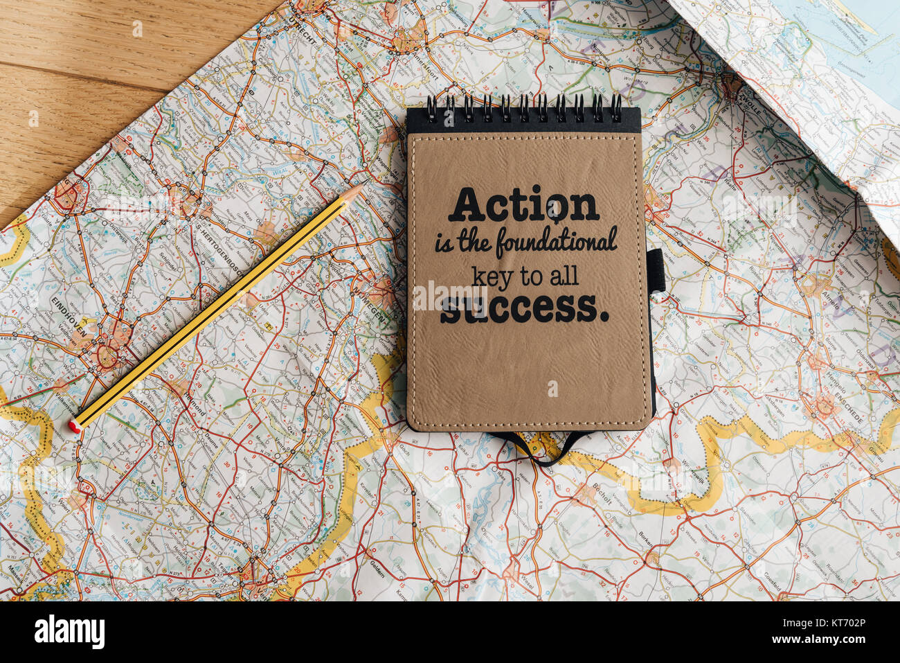 Lay flat of map, notebook with motivational quote and pencil ...