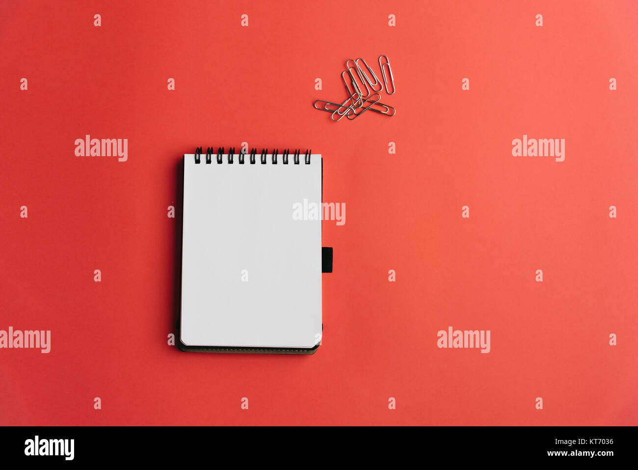 Lay flat of notebook with blank page and paperclips on bubble-gum pink ...