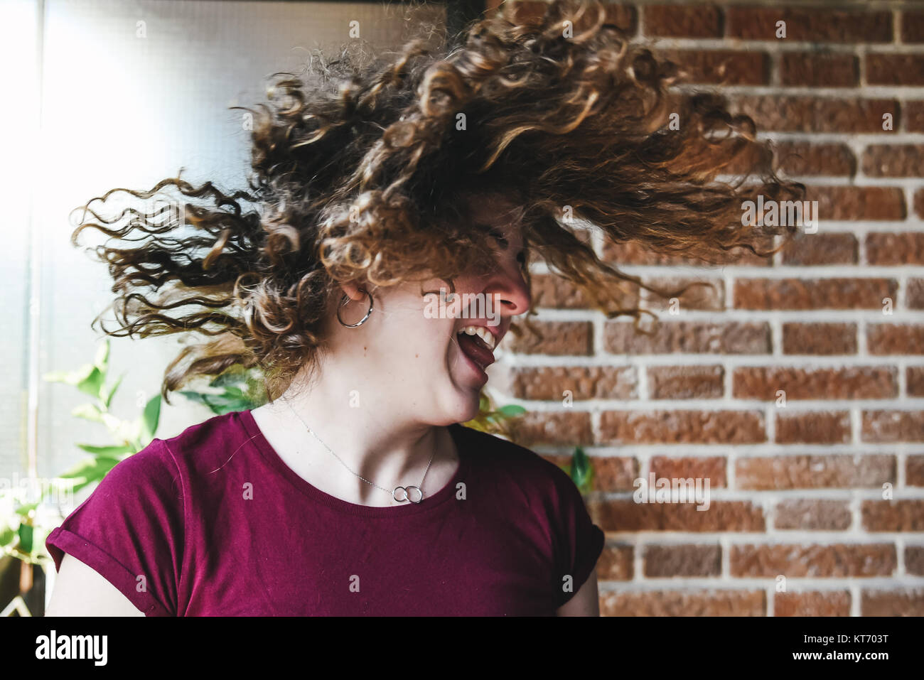 Beautiful teen girl shaking head with curly hair on brick background ...
