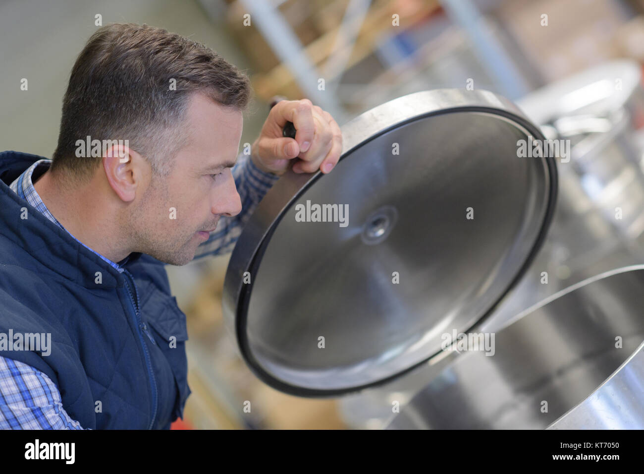 man opening a large metal container in a factory Stock Photo - Alamy