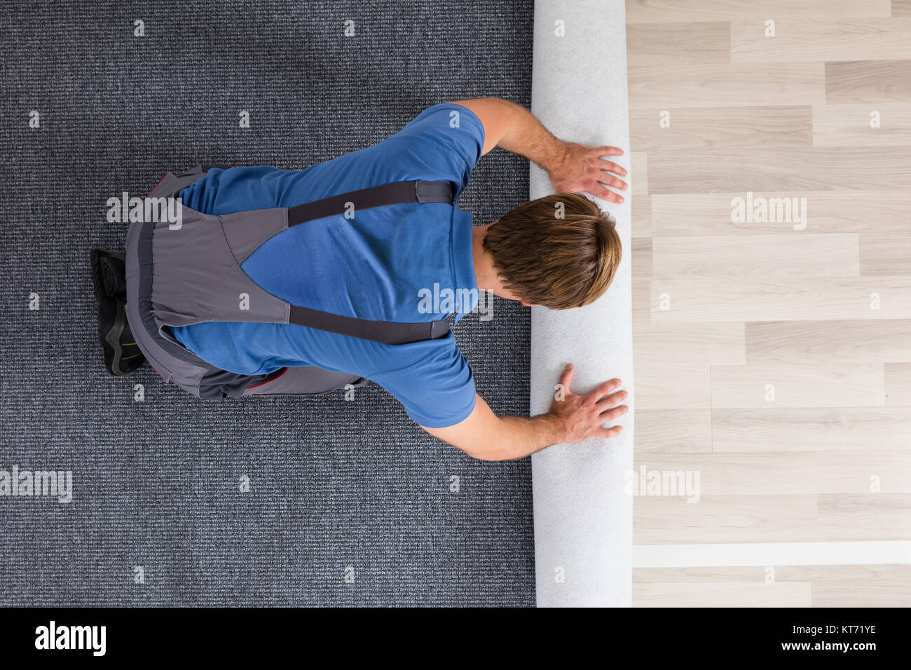 Male Worker Rolling Carpet On Floor Stock Photo - Alamy