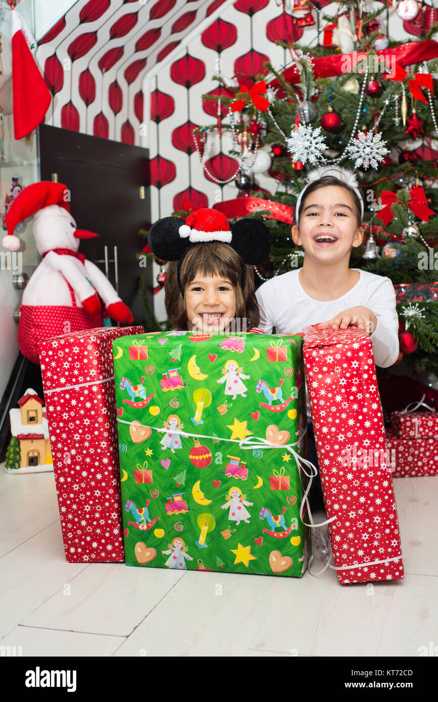 Laughing kids with Christmas gifts in front of tree in their home Stock ...