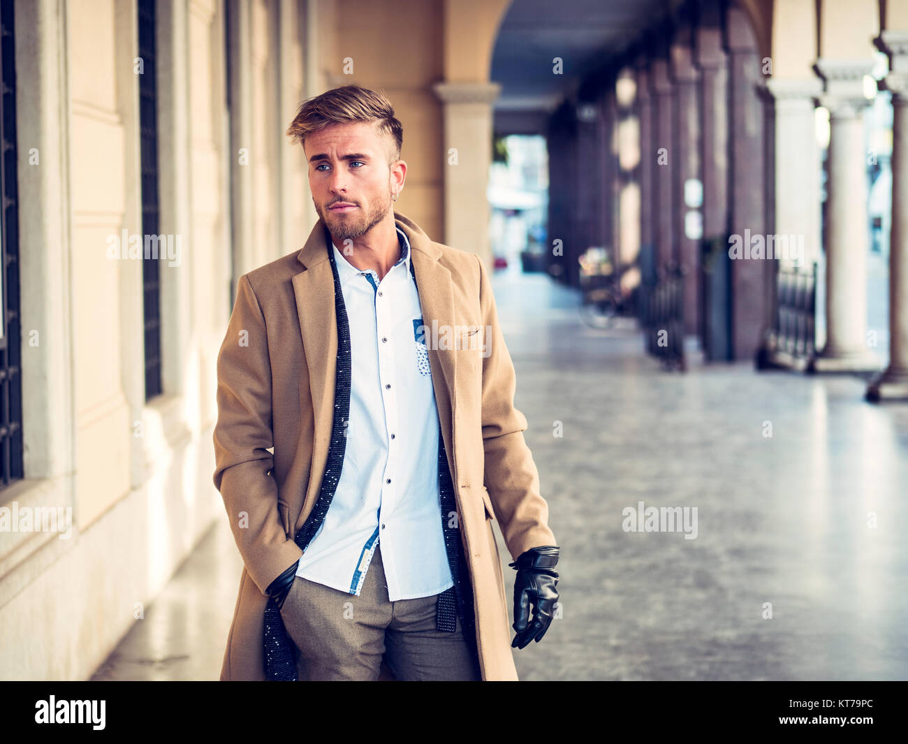 Handsome confident male model in elegant coat and gloves standing on ...