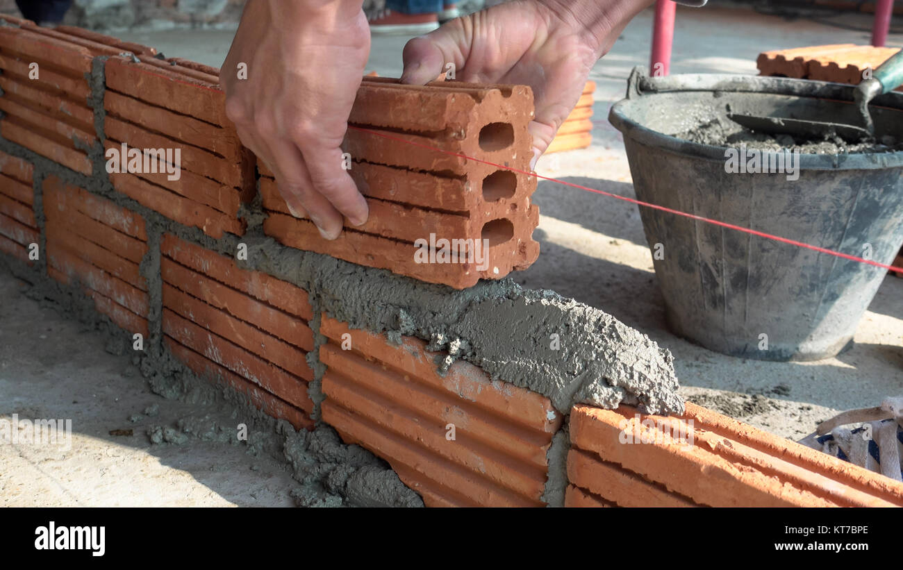 Bricklayer worker installing brick masonry on exterior wall Stock Photo ...