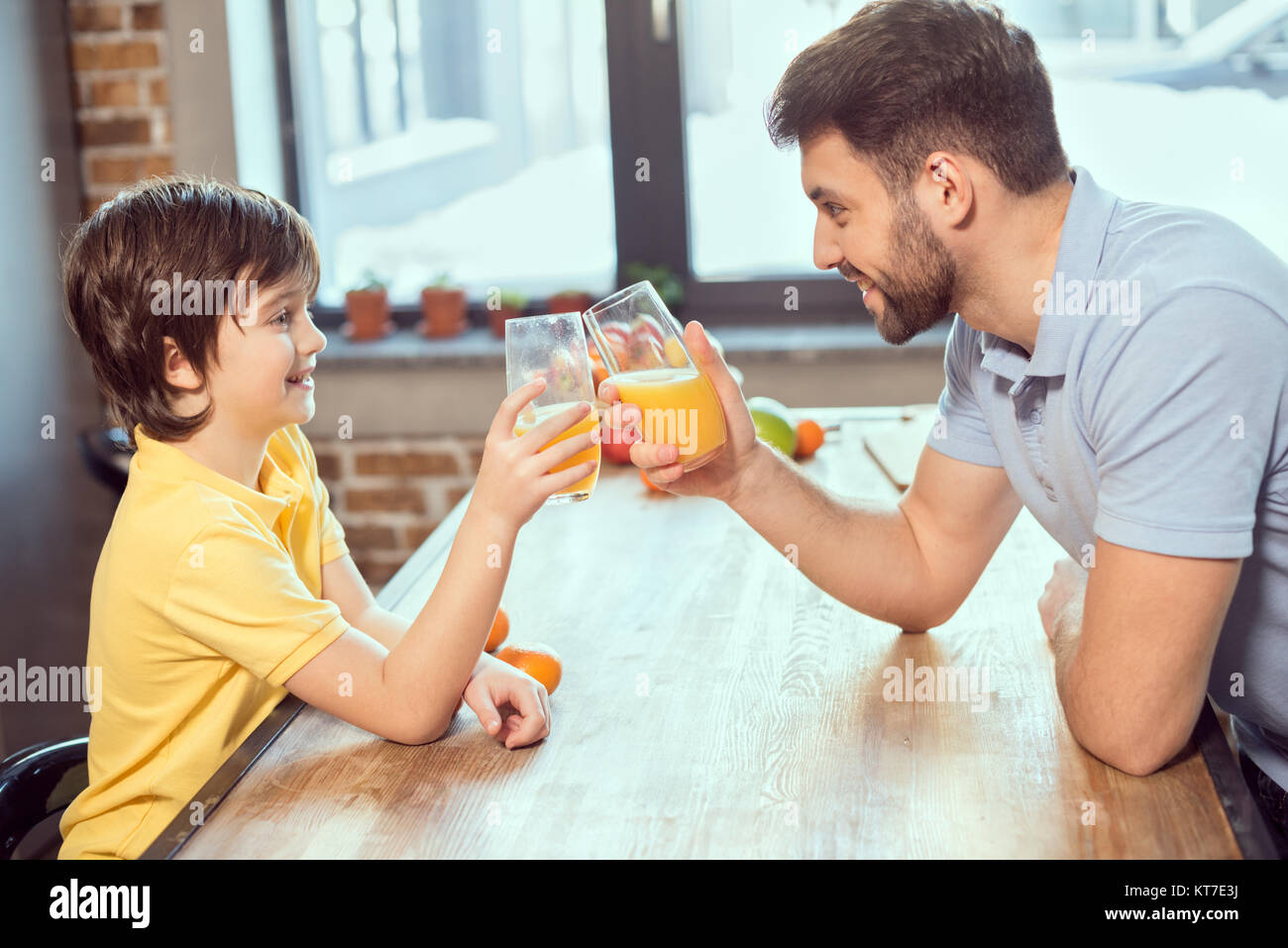 Side view of happy father and son drinking fresh juice together Stock ...