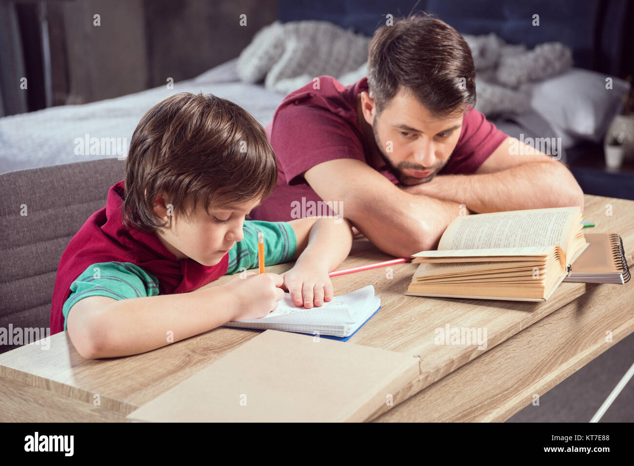 side view of father looking at concentrated son doing homework Stock ...