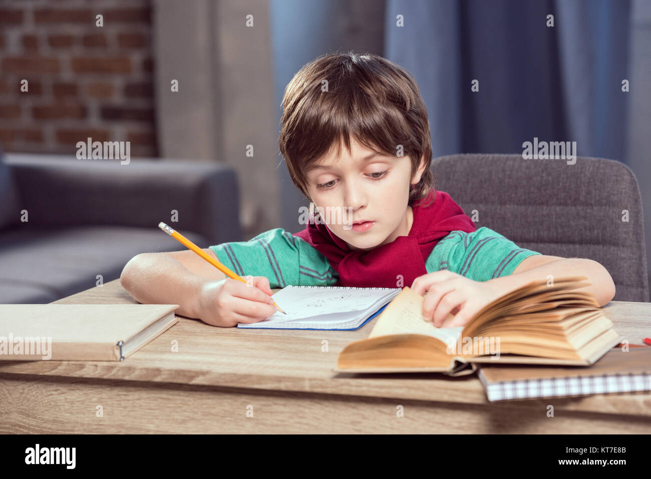 portrait of concentrated boy sitting at table and doing homework Stock ...