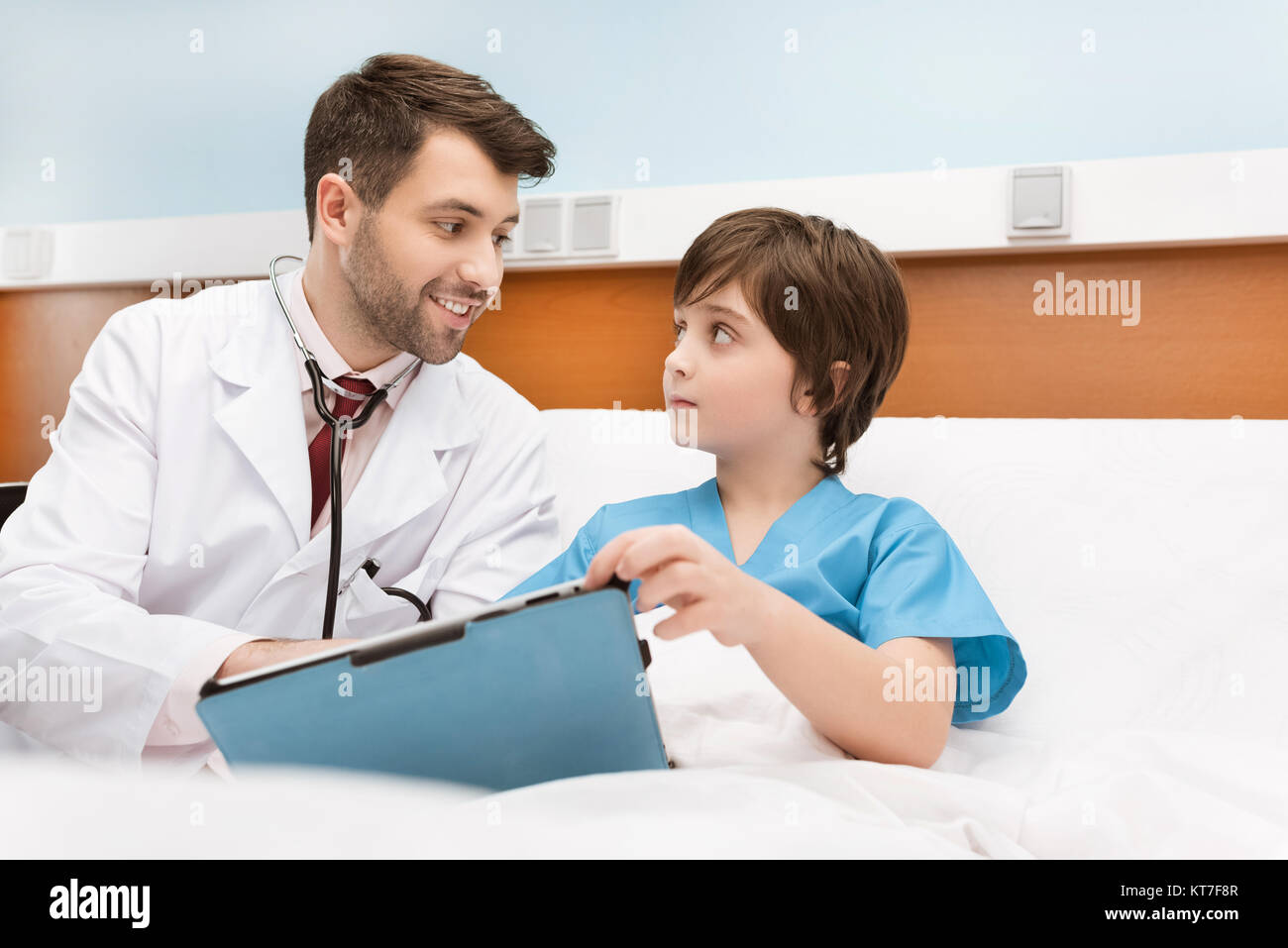 Smiling doctor and little boy patient holding clipboard and looking at ...