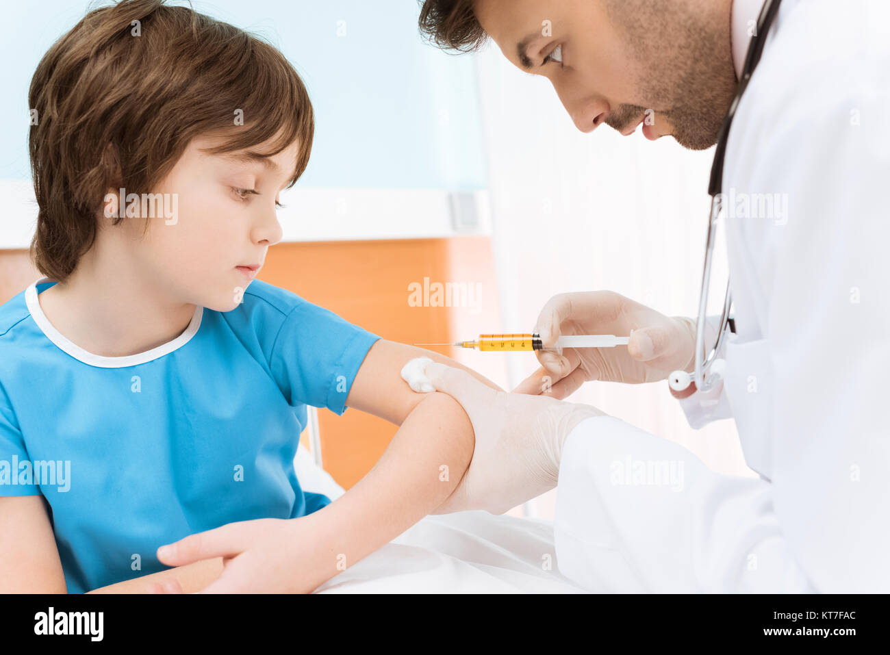 side view of doctor making injection to boy patient in bed Stock Photo ...