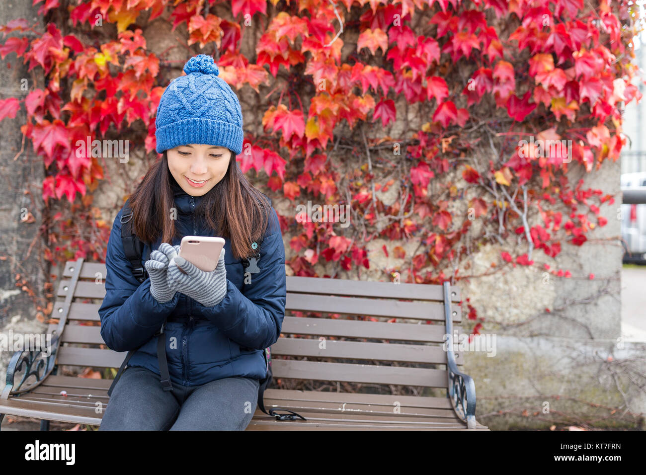 Woman using cellphone and sitting down on bench Stock Photo - Alamy