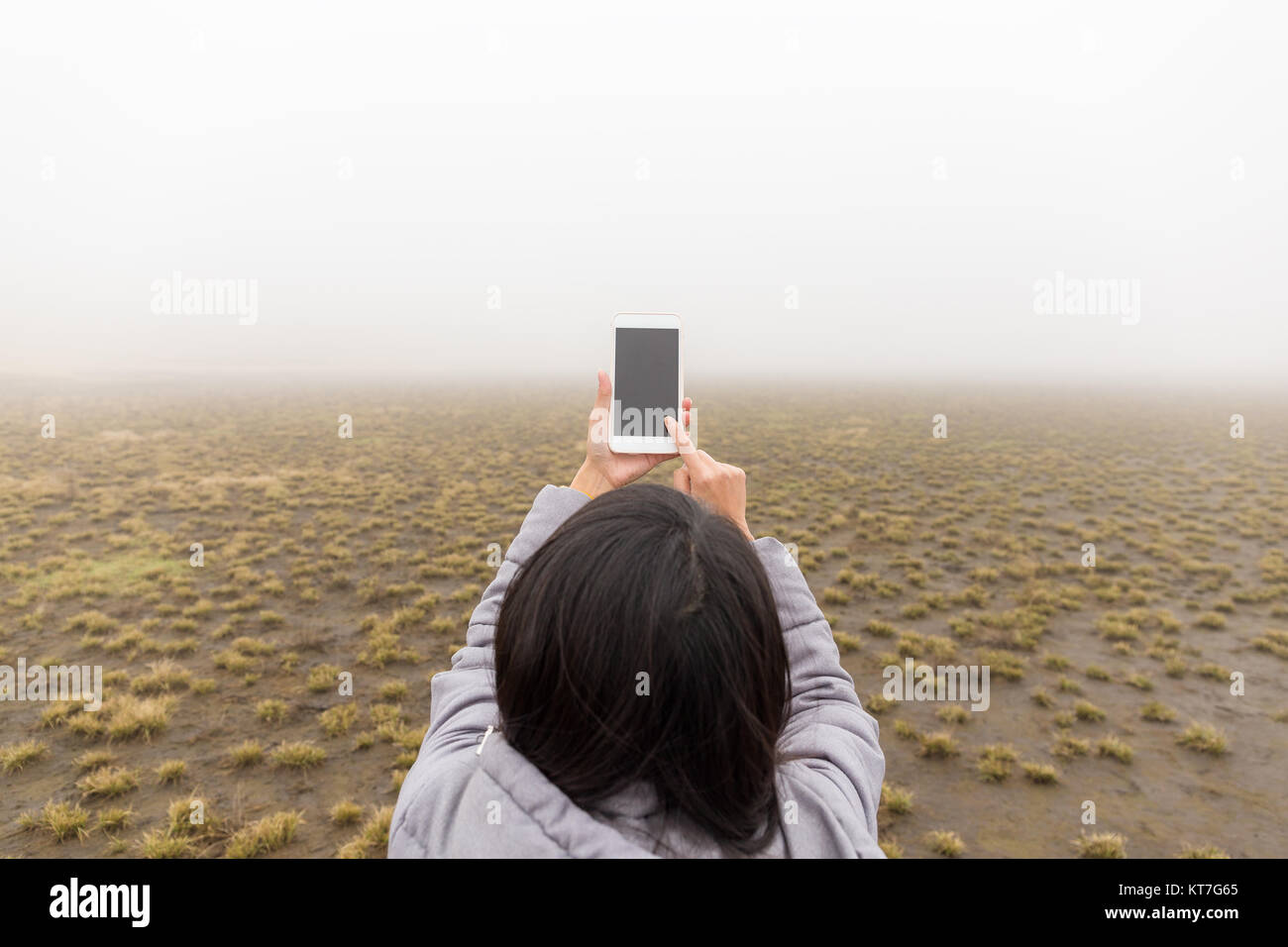 Back view of woman taking photo with fog Stock Photo - Alamy