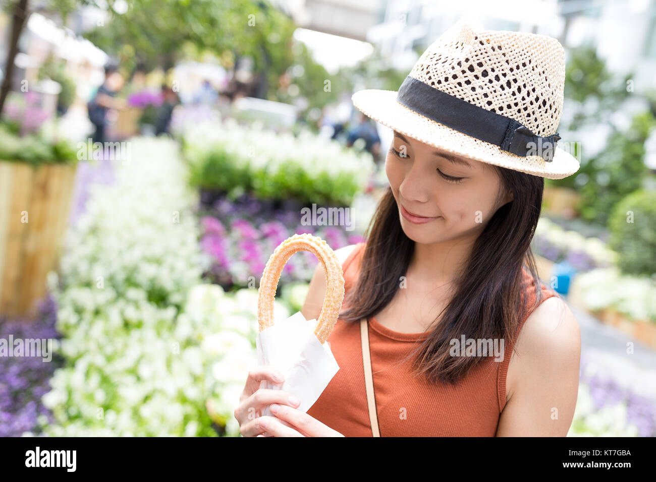 Young Woman holding Spanish churro in flower garden Stock Photo - Alamy
