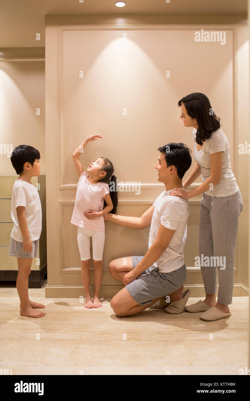 Cheerful young parents measuring their children's height Stock Photo ...