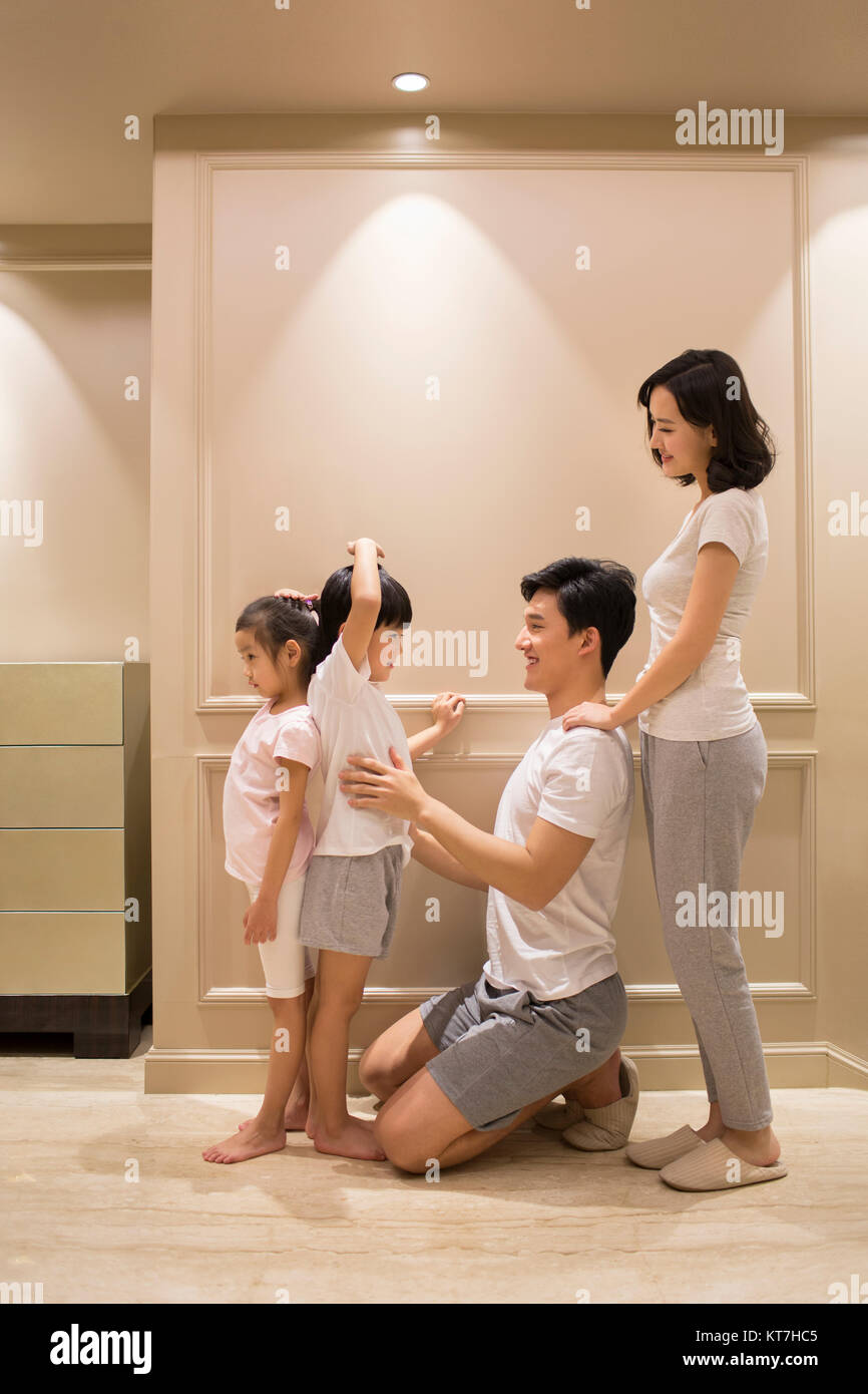 Cheerful young parents measuring their children's height Stock Photo ...